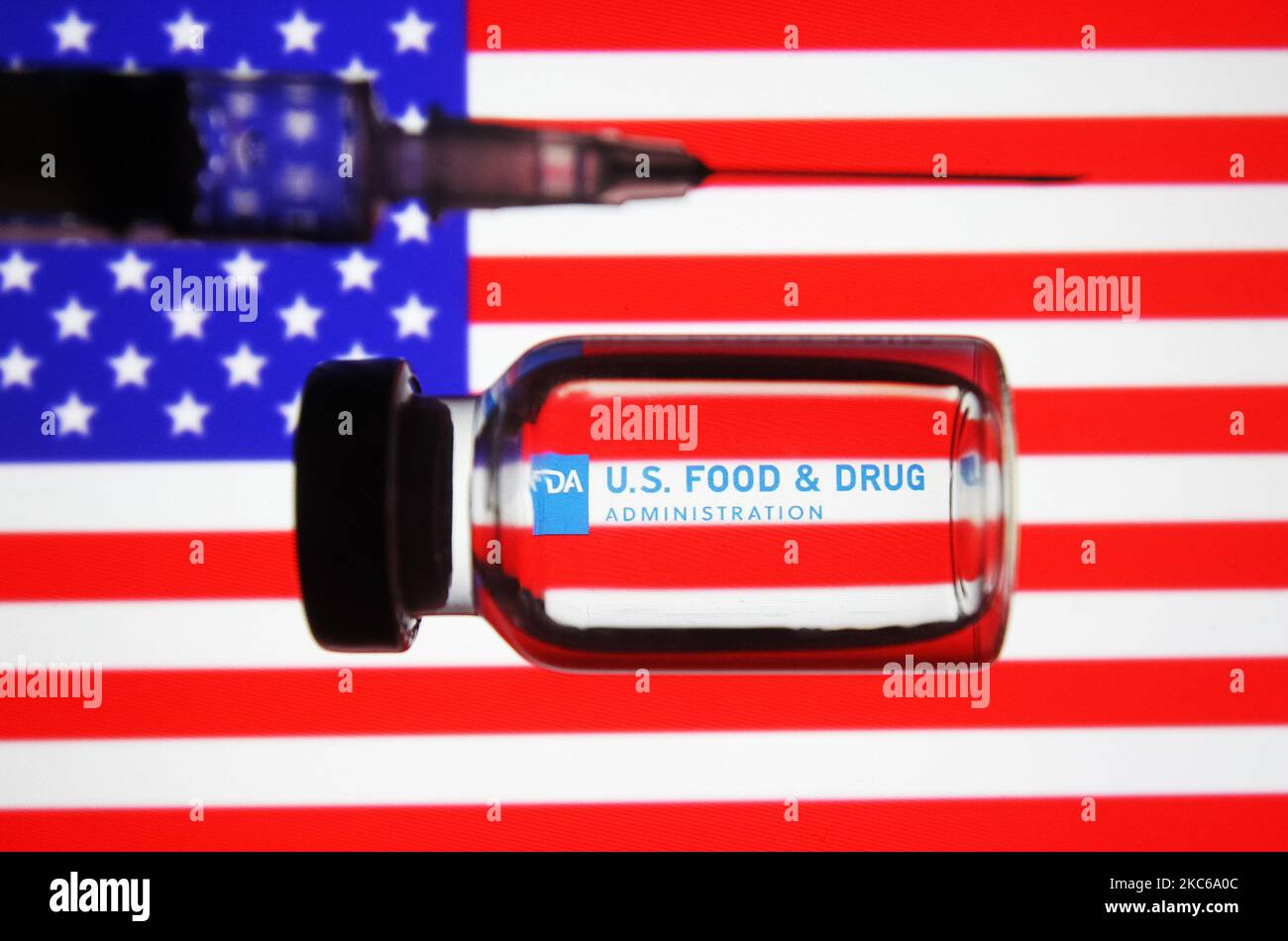 A medical syringe and a vial are seen in front of the United States ...