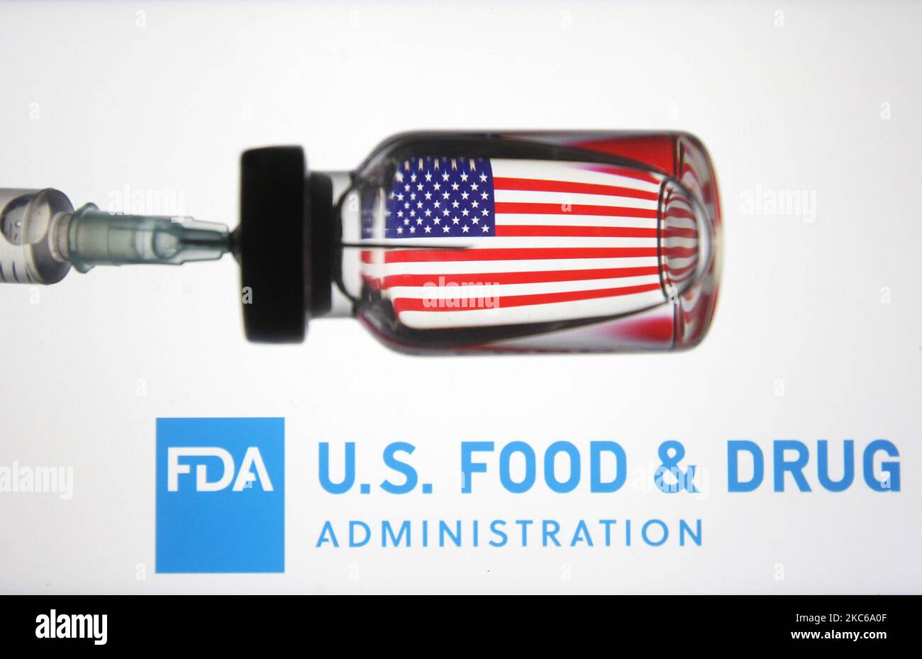 A medical syringe and a vial are seen in front of the United States ...