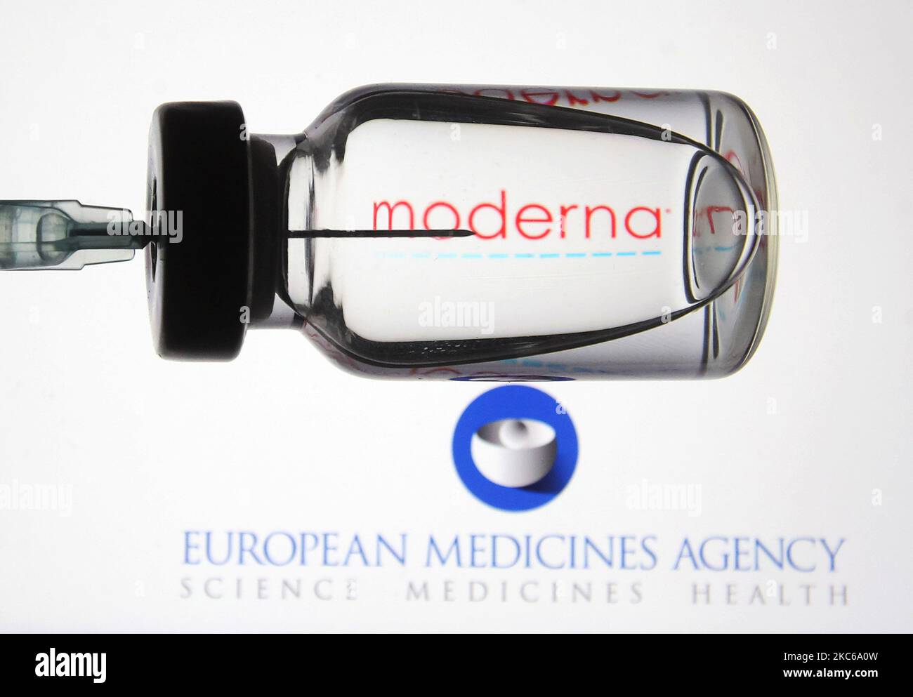 A medical syringe and a vial are seen in front of Moderna and the ...