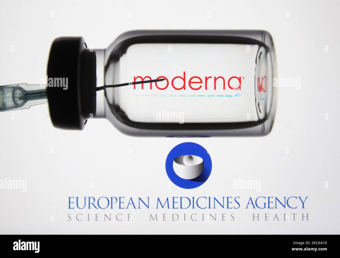 A medical syringe and a vial are seen in front of Moderna and the ...