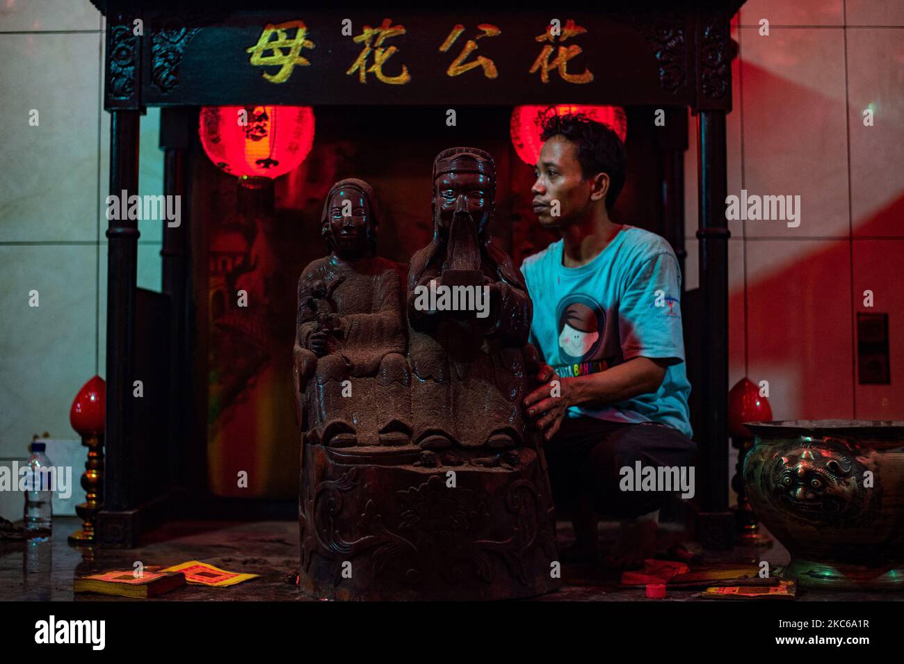 A worshiper cleans a statue at Toasebio Temple in Glodok, West Jakarta ...