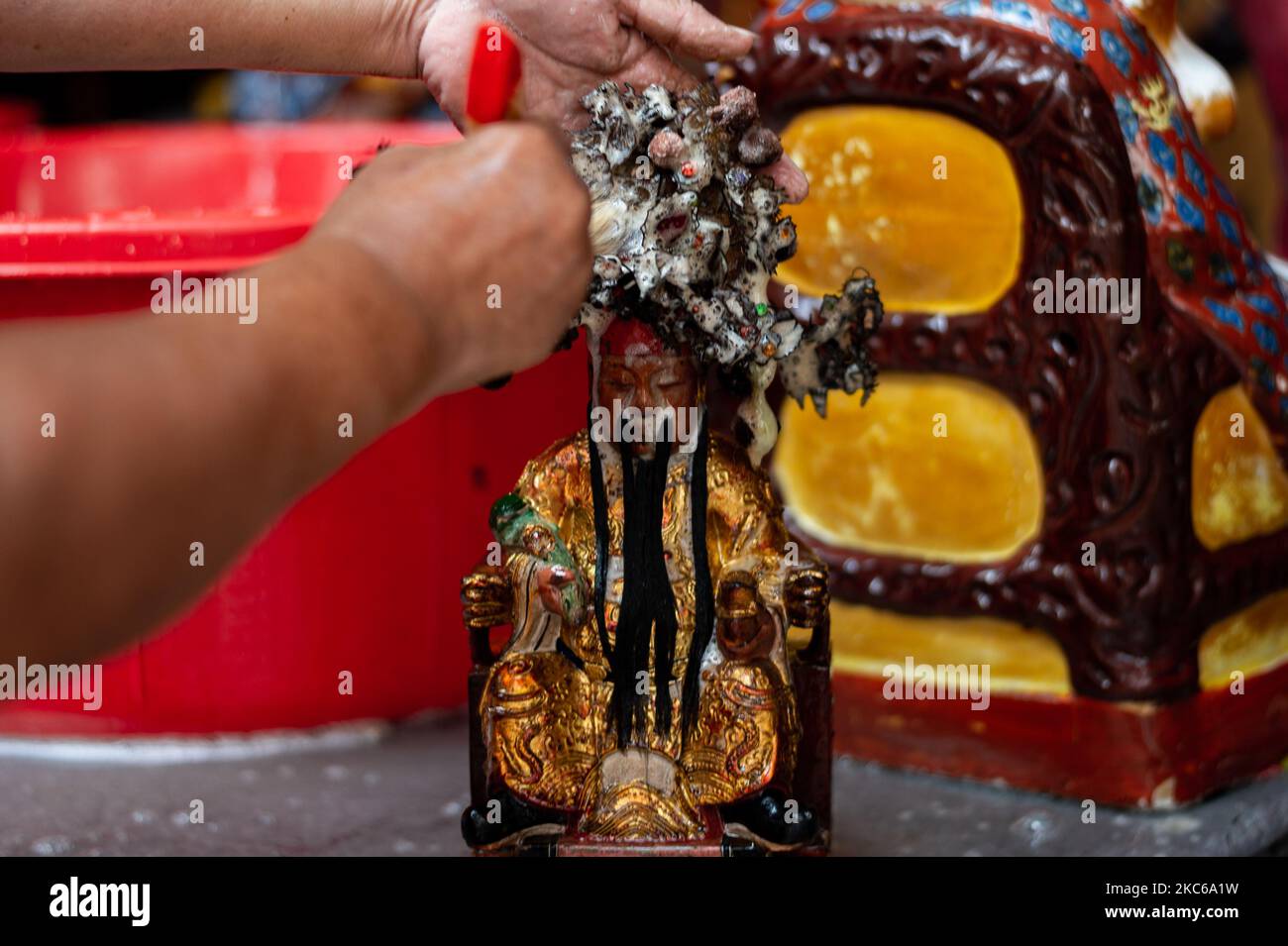 A worshiper cleans a statue at Toasebio Temple in Glodok, West Jakarta ...