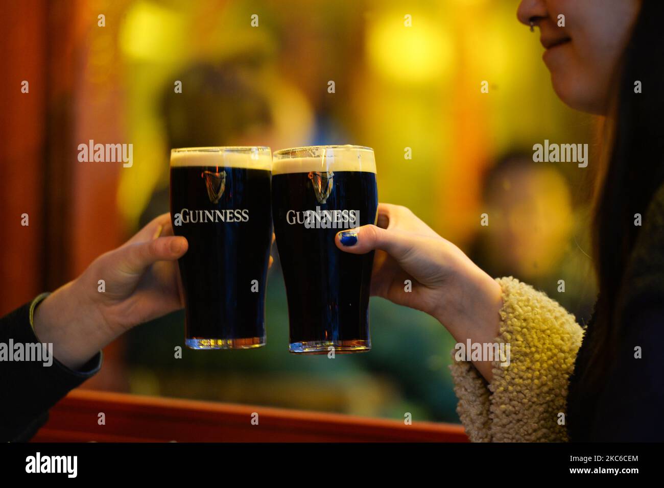 Two young ladies enjoy a pint of Guinness on a bar-restaurant terasse ...