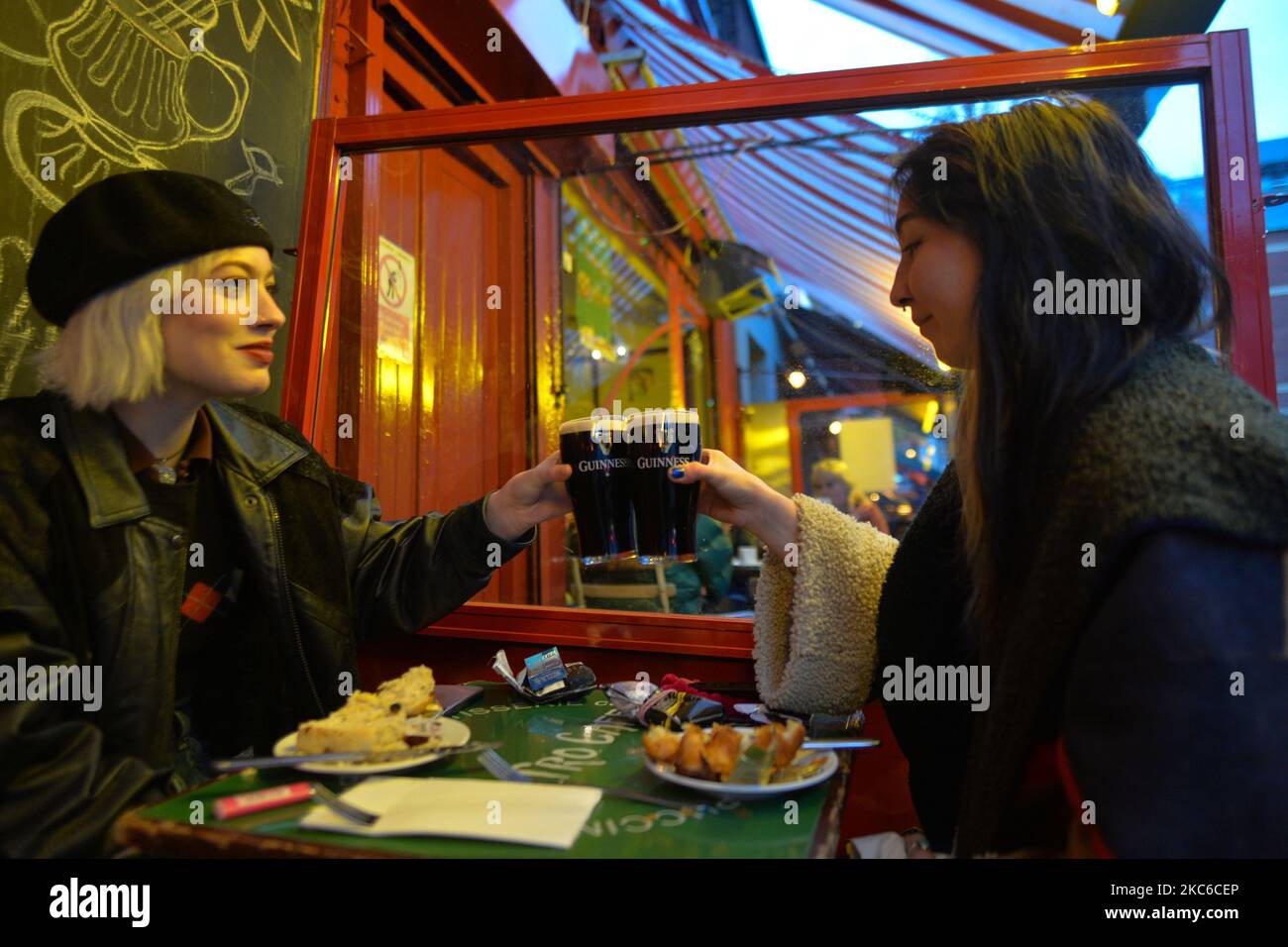 Two young ladies enjoy dinner and a pint of Guinness on a bar ...