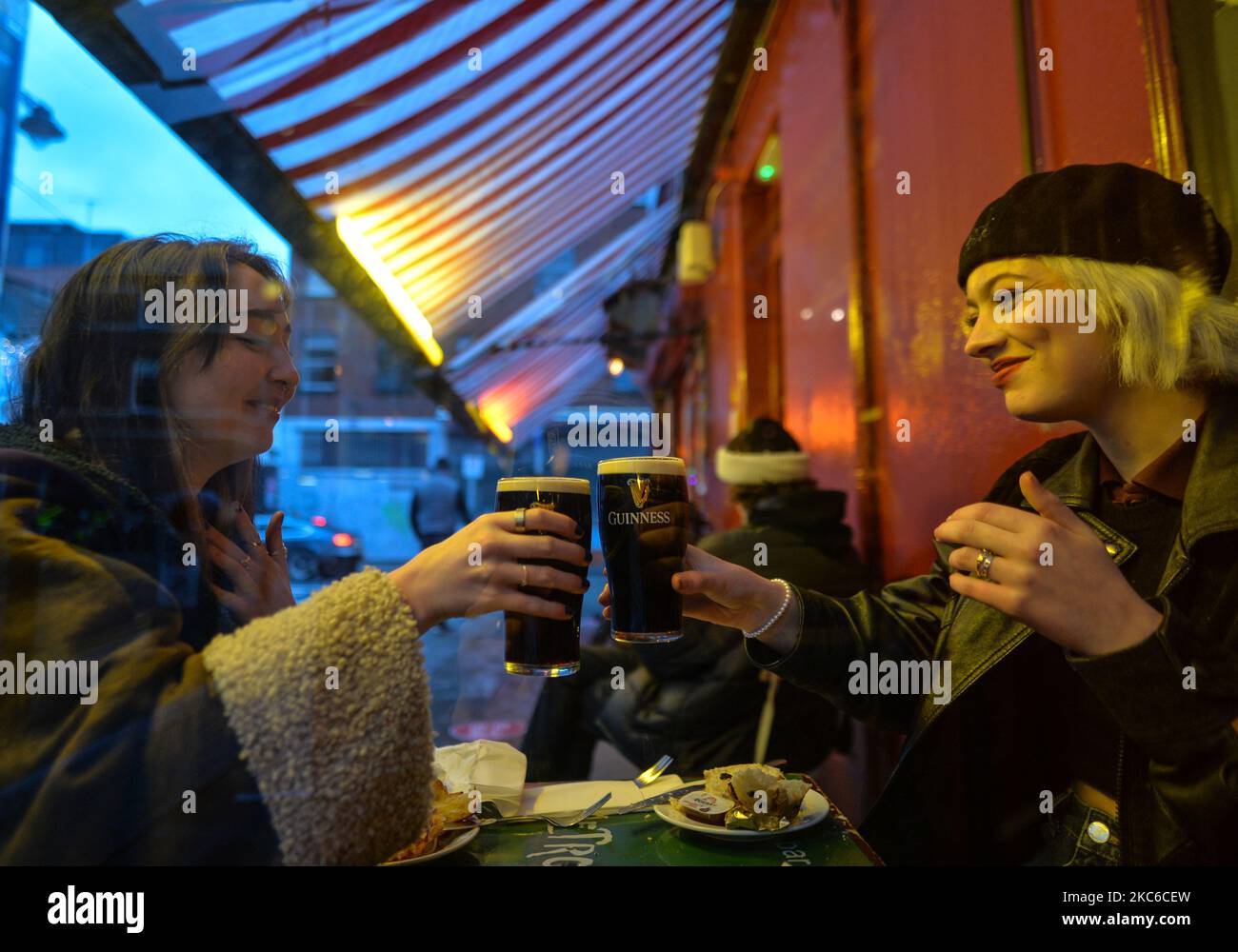 Two young ladies enjoy dinner and a pint of Guinness on a bar ...
