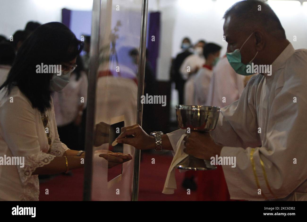 A Christian devotee receives a communion from a priest at Katedral ...