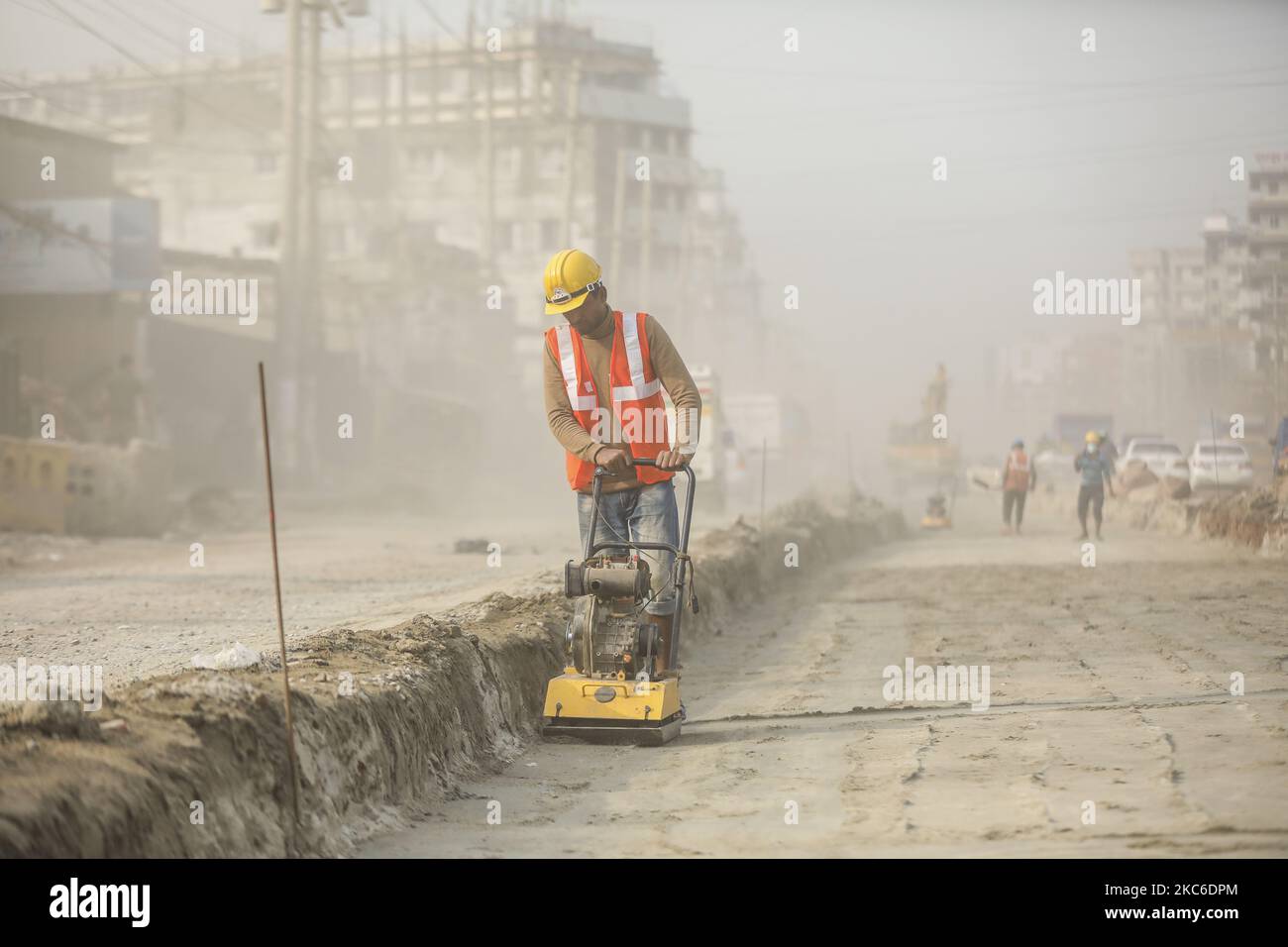 A Bangladeshi construction worker walks through a dusty busy road in Gazipur near Dhaka ...