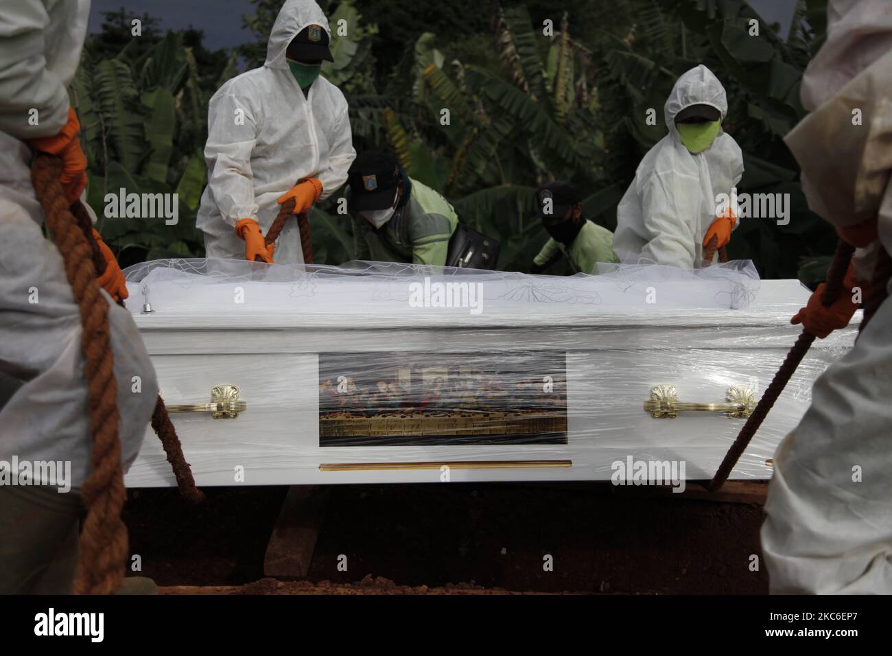 Funeral workers wearing persoal protective equipment (PPE) bury the ...