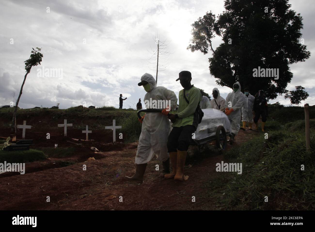 Funeral workers wearing persoal protective equipment (PPE) bury the ...