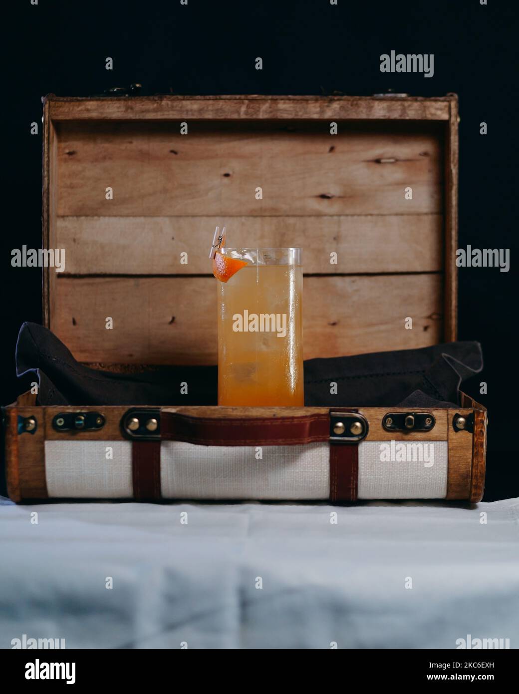 A vertical shot of a delicious orange cocktail inside a chest in a bar ...