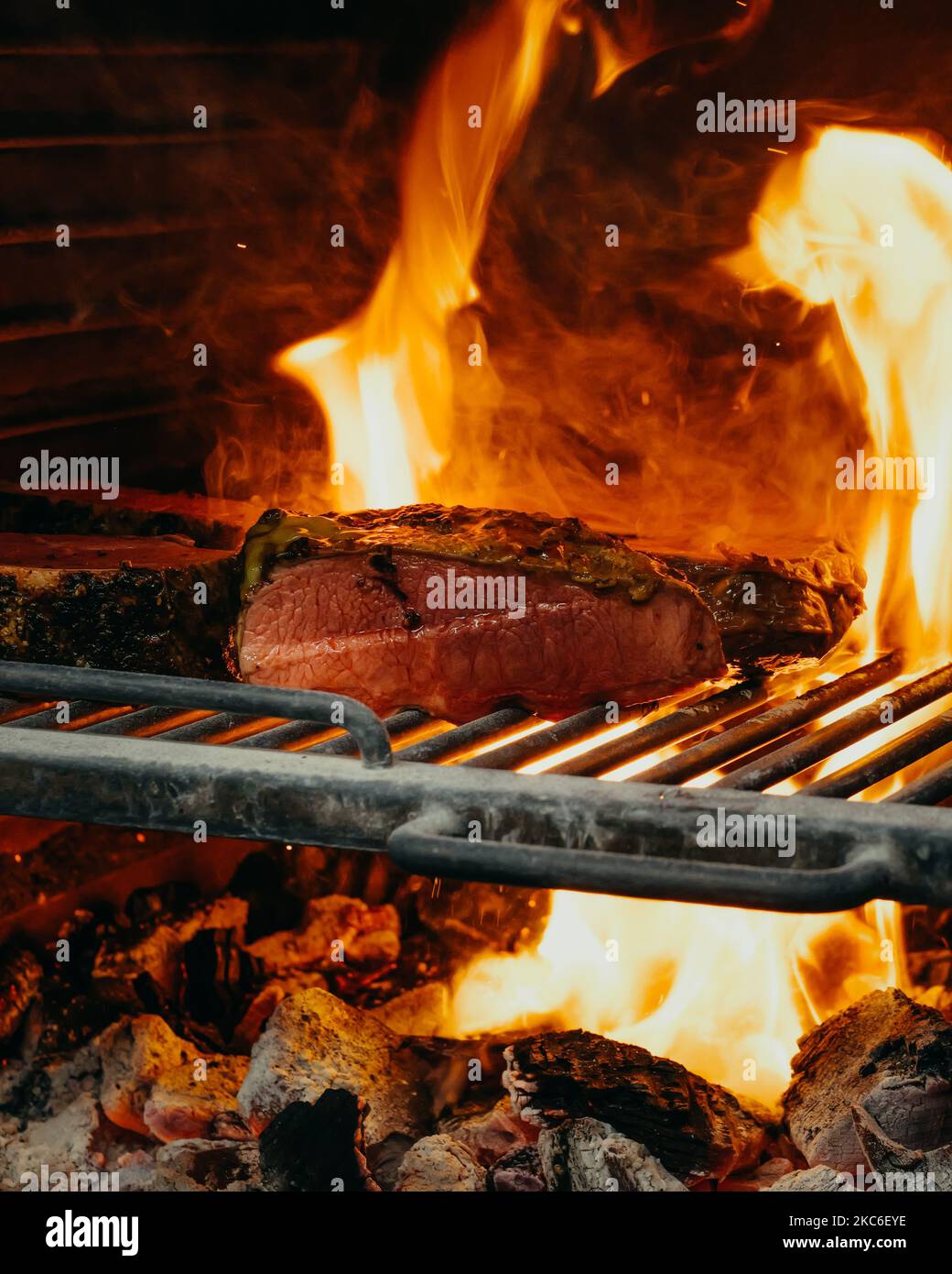 A closeup of a delicious steak being cooked with open flames in a ...