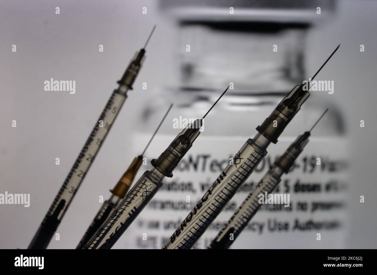 An illustrative image of medical syringes seen in front of an image of ...