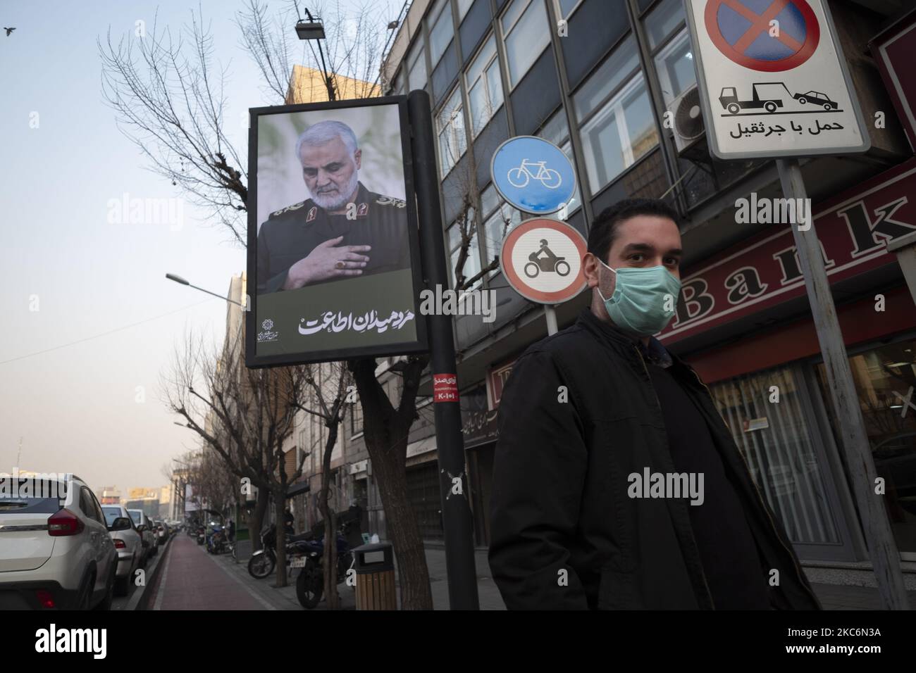 An Iranian man wearing a protective face mask looks on as he walks past ...