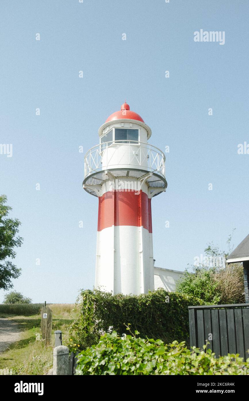 A low angle view of red and white lighthouse under blue bright sky ...