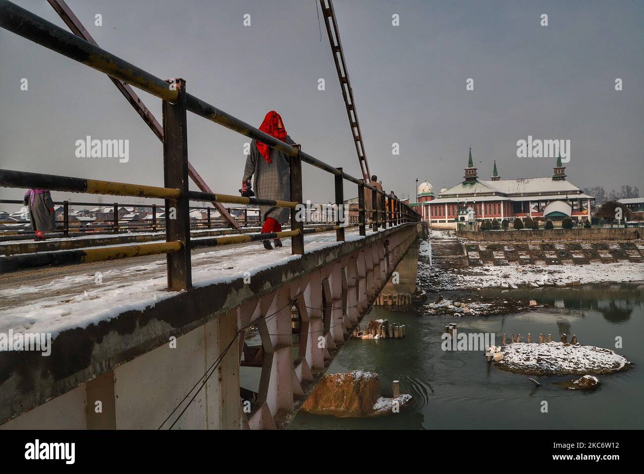 A woman walks over a bridge near Jama Masjid after fresh snowfall in ...