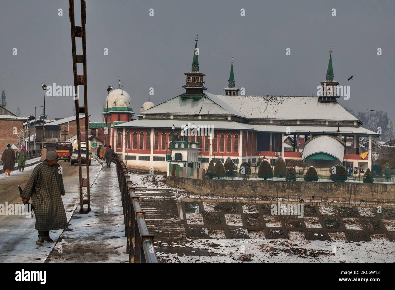 Kashmiri men walk over a bridge near Jama Masjid after fresh snowfall ...