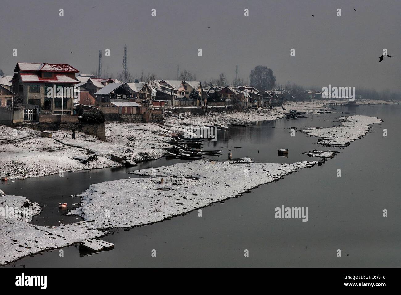 A man walks near the residential houses on the banks of river Jhelum ...