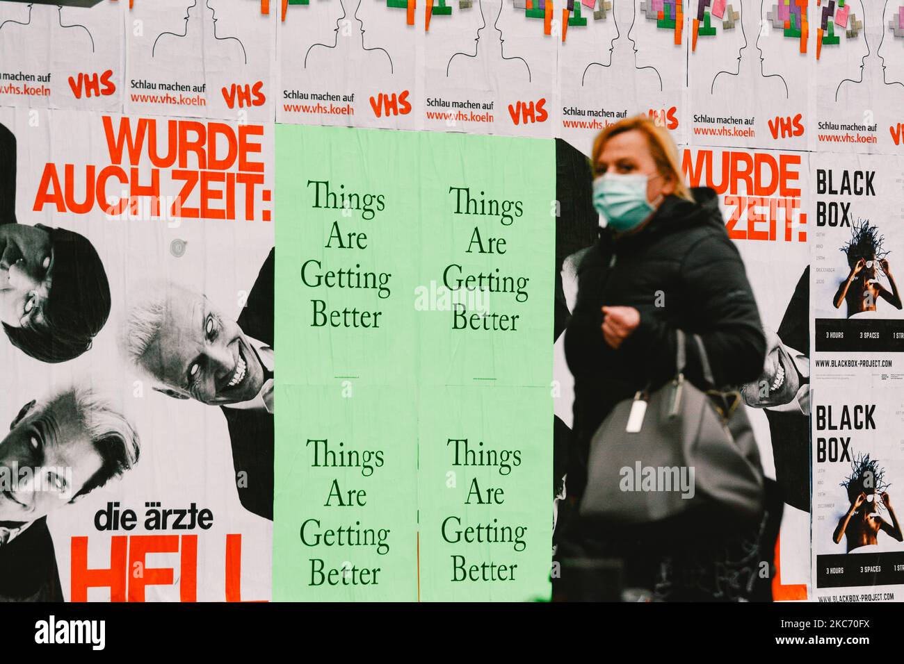 A woman with face mask walking pass posters with message ''things are ...