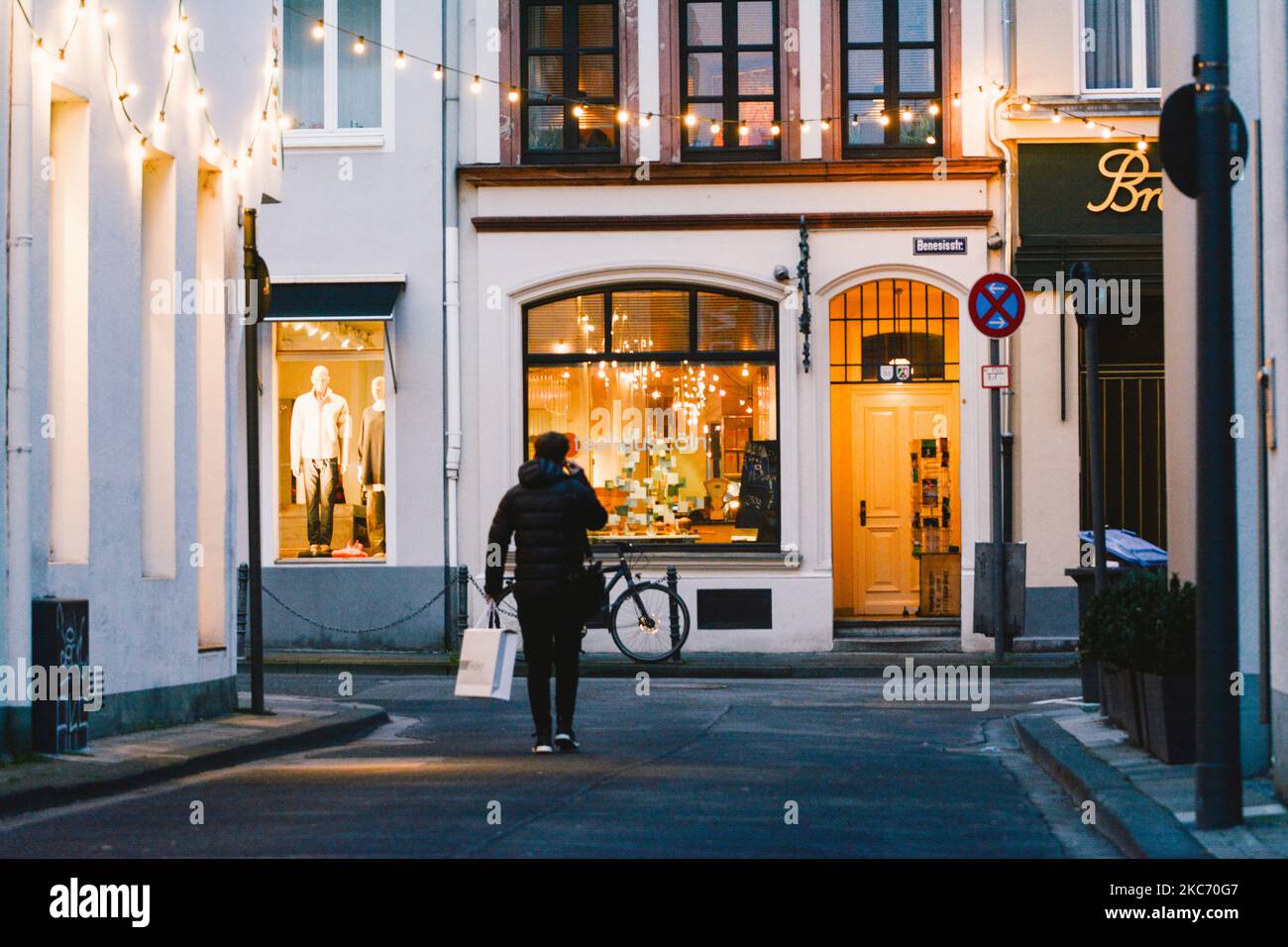 A shopper with a shopping back walks in a nearly empty shopping street ...