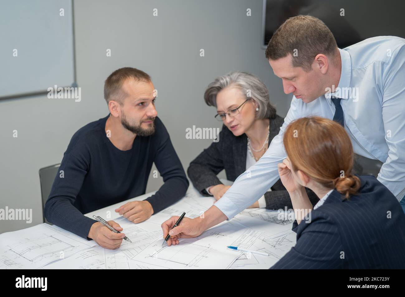 The boss gives instructions to three employees in the office conference ...