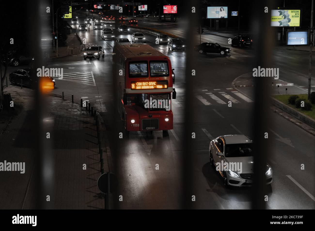 The boulevard in Skopje at night with a red bus seen behind balcony ...