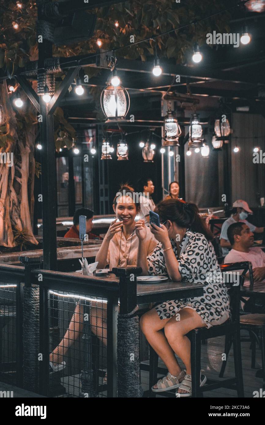 A vertical shot of young women chatting in a cafe at night Stock Photo ...