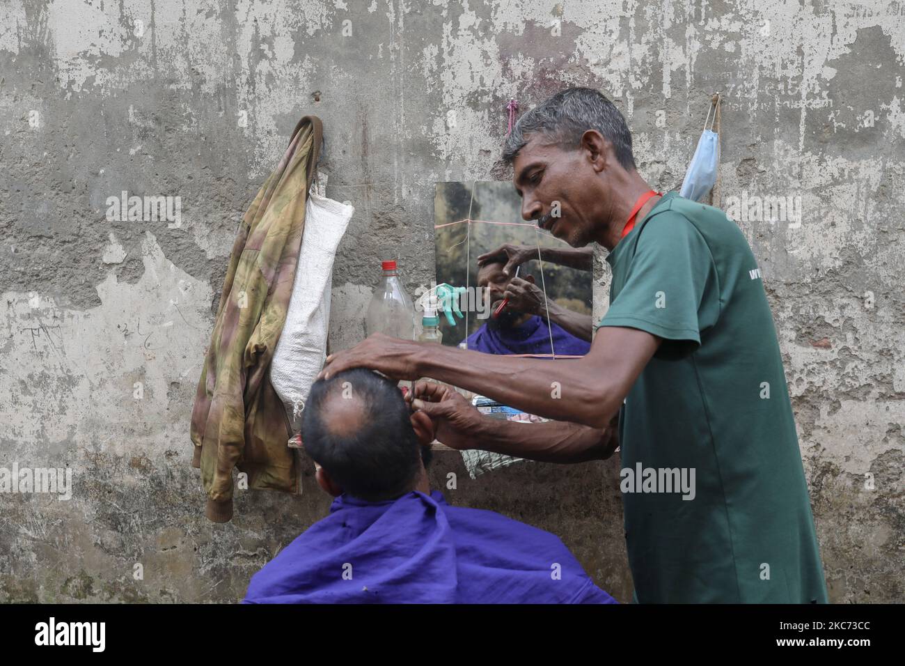 A street barber provides hair cut service to a customer at Tejgaon Railway line in the Tejgaon ...