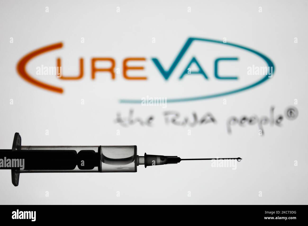 Medical syringe is seen with CureVac logo displayed in the background ...