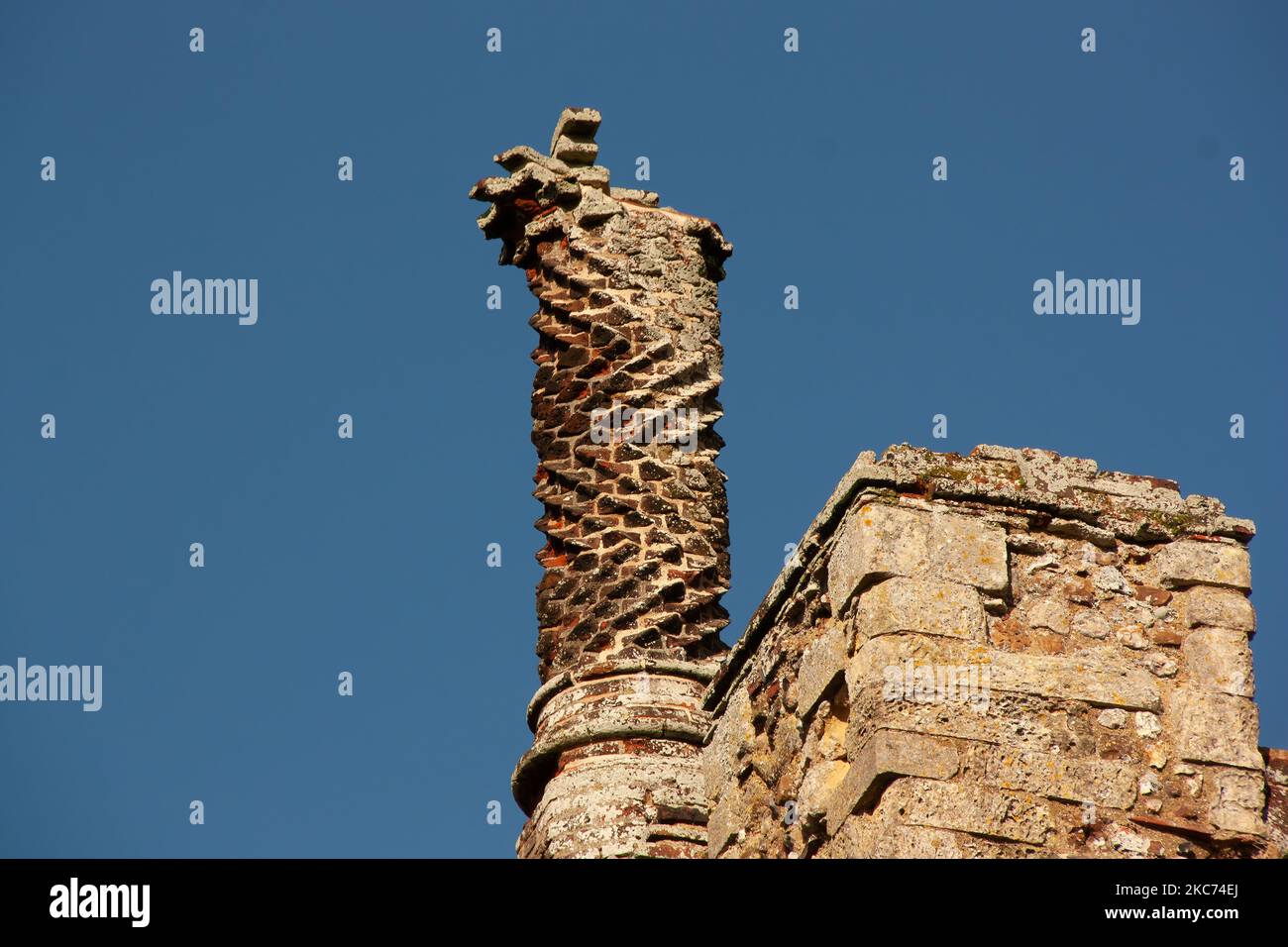 An Ancient weathered ornate damaged chimney stack against blue sky ...