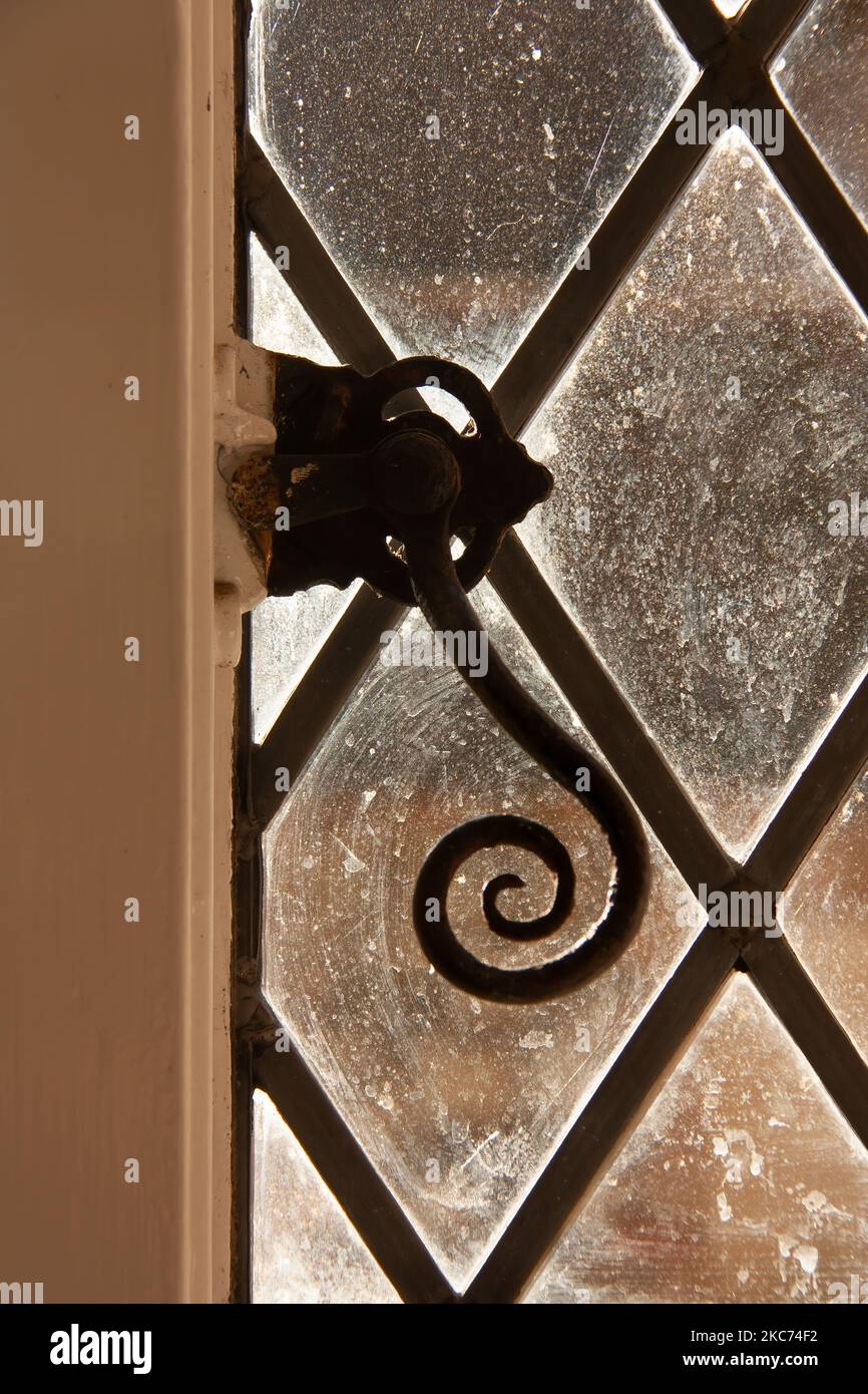A closeup of an ancient window latch with thick glass plate window ...