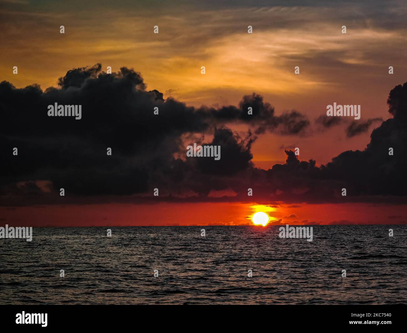 A breathtaking view of bright sun in dark cloudy sunset sky shining ...