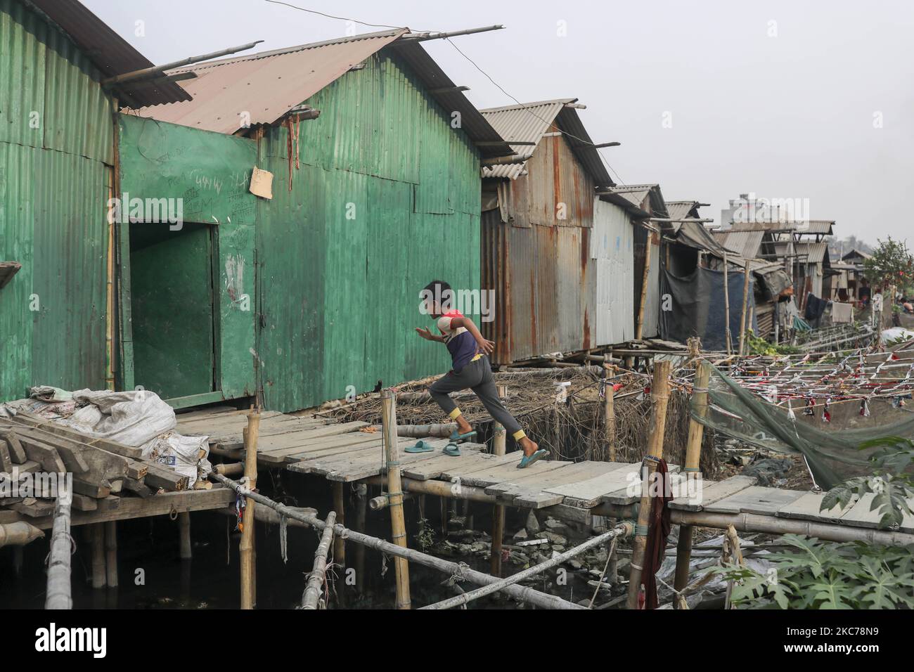 A boy is runing ia a slum area beside a railway in Dhaka, Bangladesh on ...