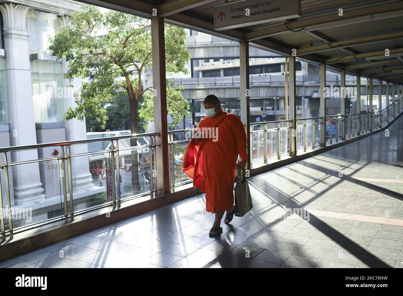 A monk wearing protective face mask walks a past skywalk amid a new ...
