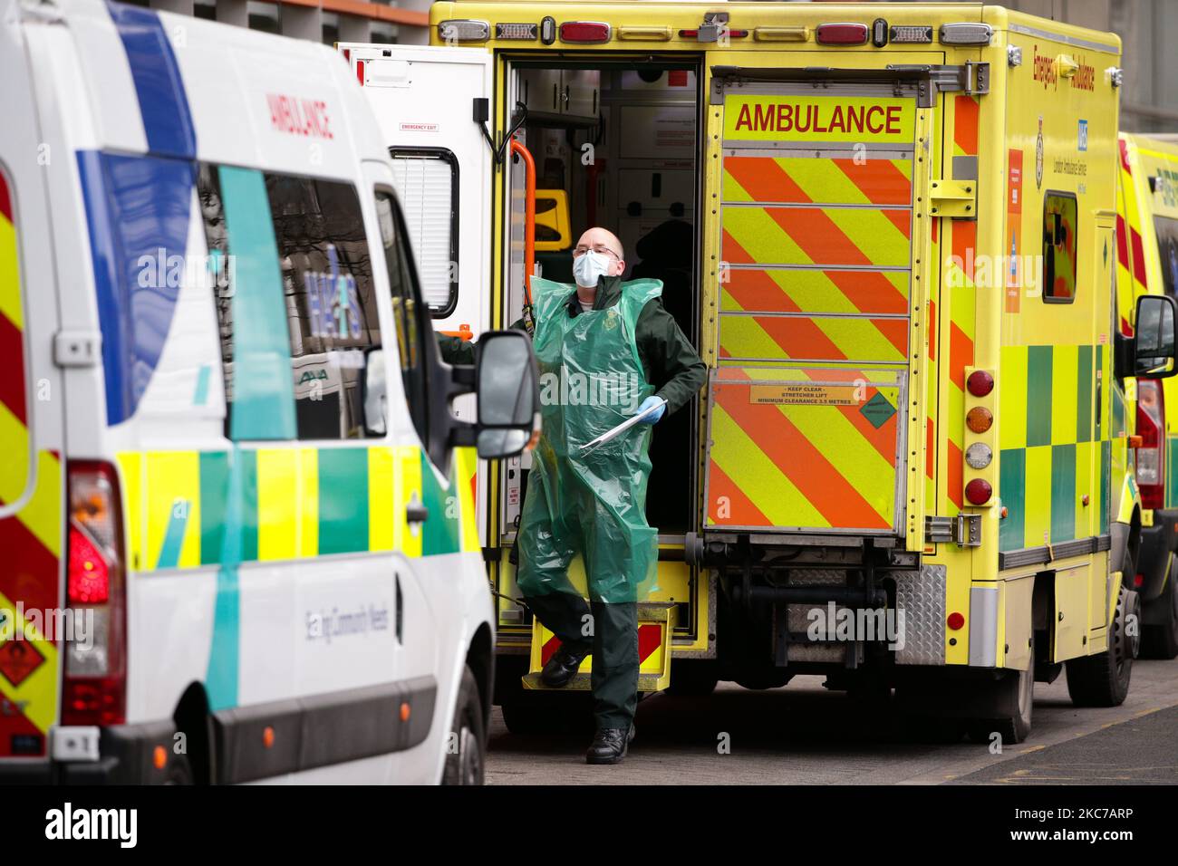 A paramedic wearing PPE exits an ambulance outside the emergency ...