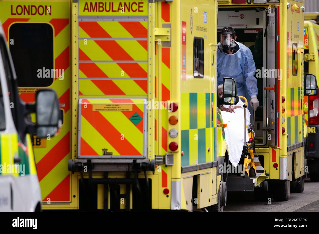 A medic wearing PPE takes a patient wearing an oxygen mask out of an ...