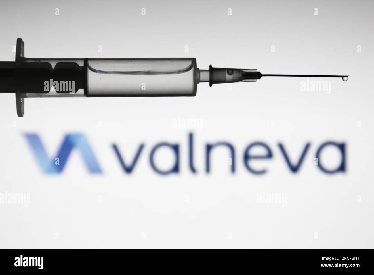 Medical syringe is seen with Valneva company logo displayed on a screen ...