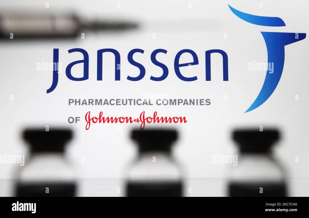 A medical syringe and vials are seen in front of logo of Janssen ...