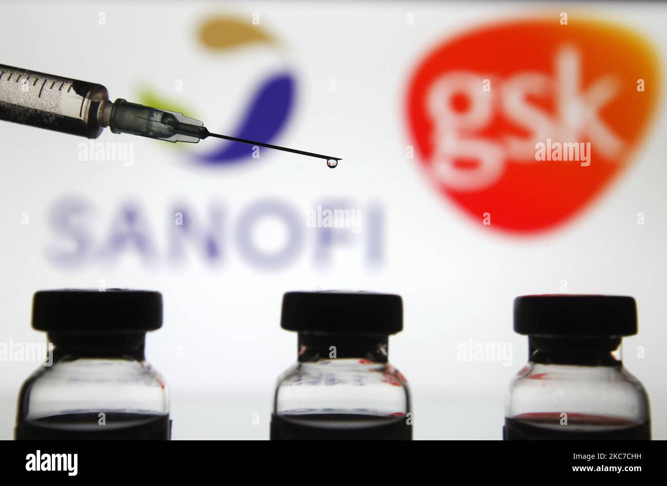 A medical syringe and vials are seen in front of Sanofi and ...