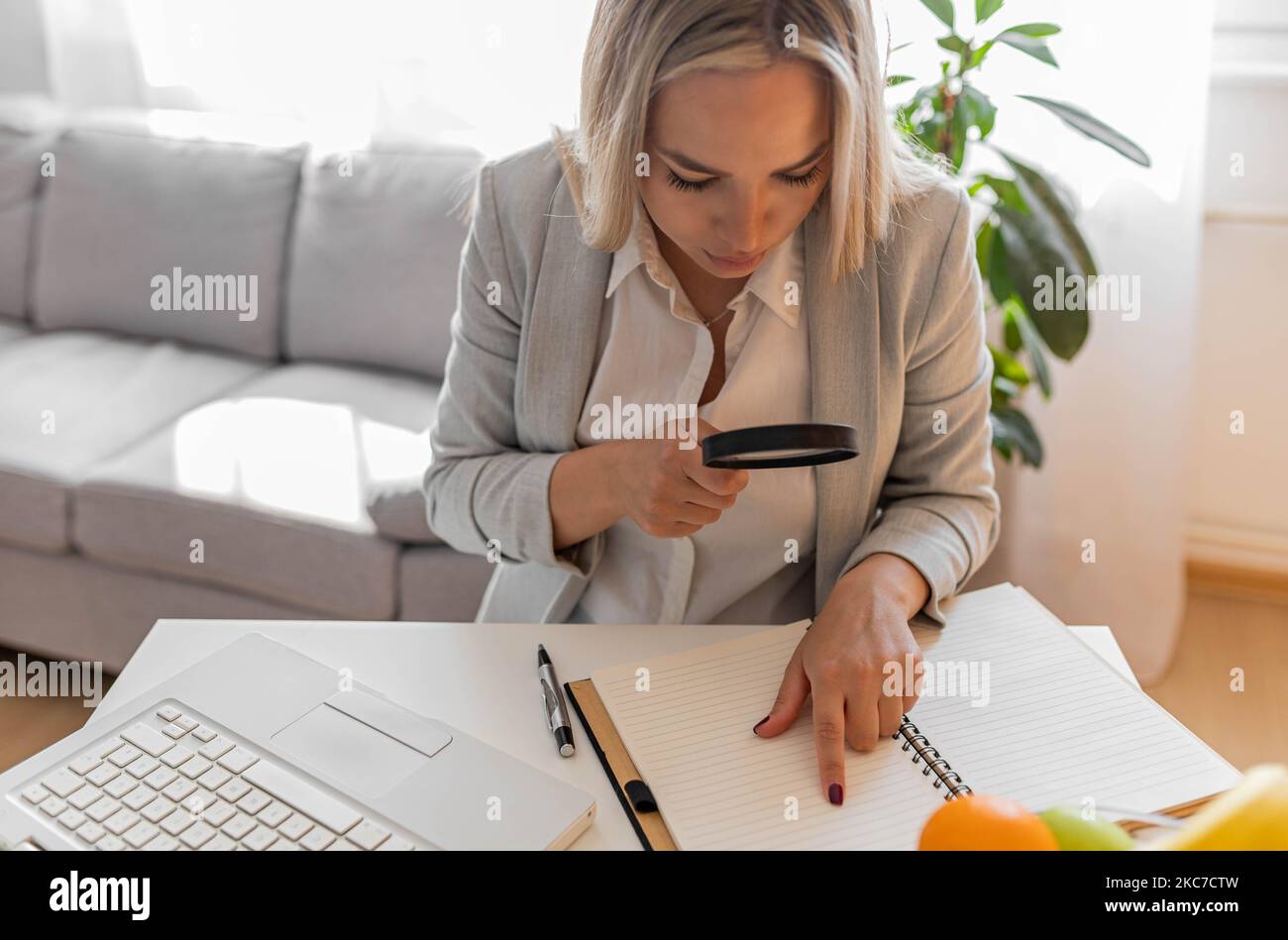 Curious young business woman looking through a magnifying glass in her ...