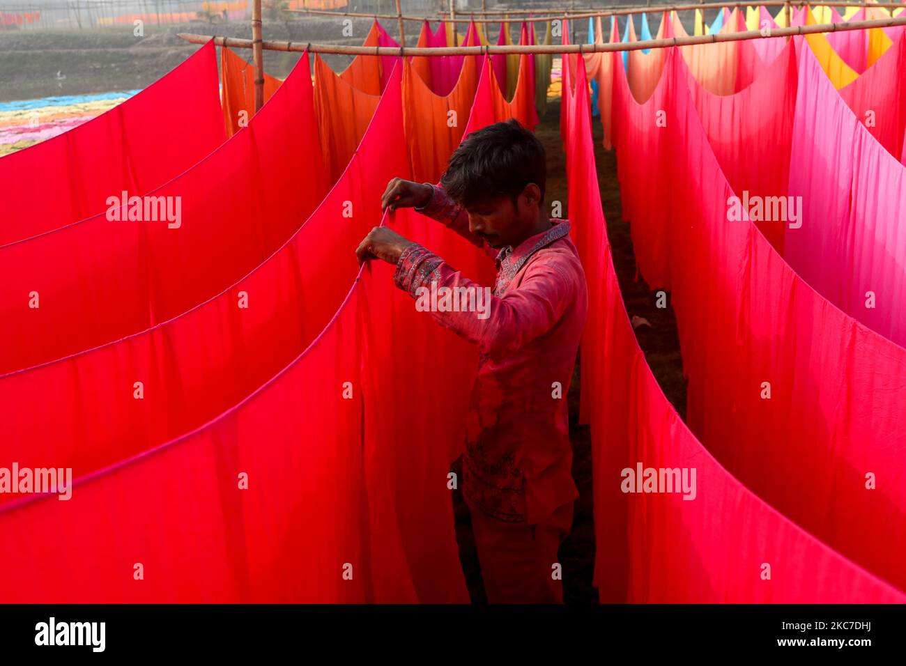 A worker dries fabrics after applying color at a dye factory at ...