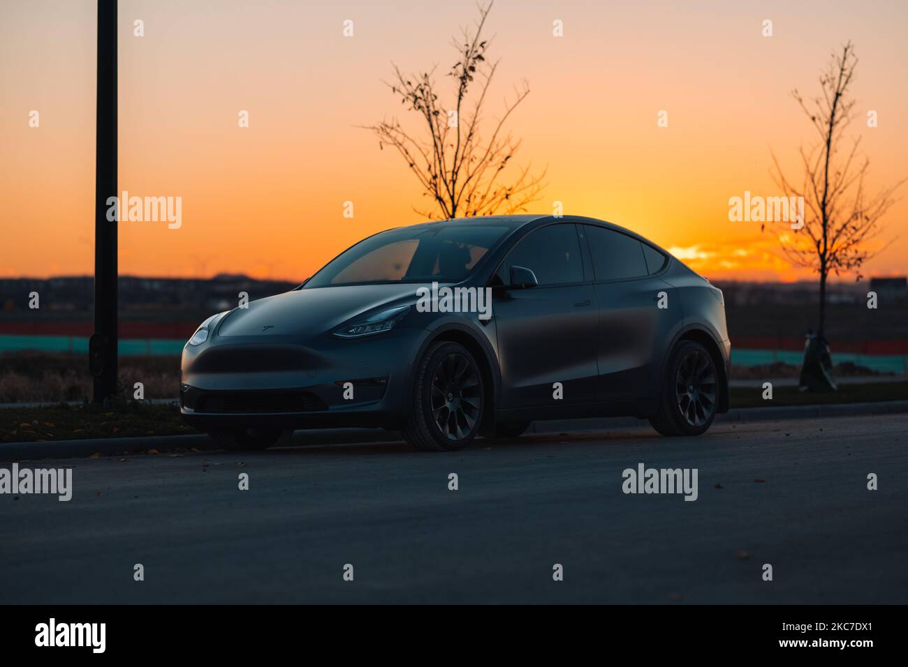 Dramatic picture of a Tesla model Y parked on the road with an orange ...