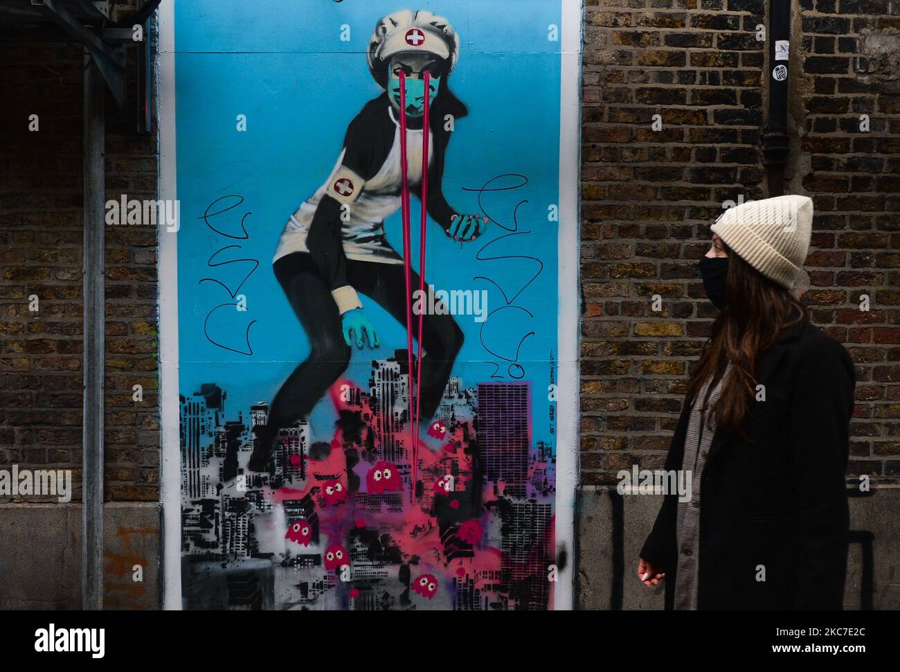 A young woman walks by the mural '50 FT HEROES' by the Irish artist ...
