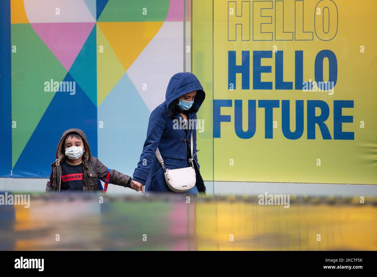 A mother and son in face masks in the rain on Market Street during a ...