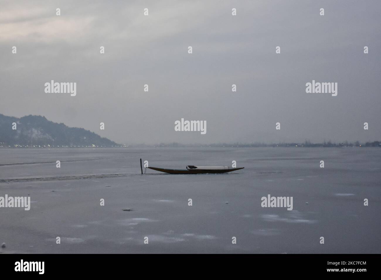 A stranded shikara remains stuck in ice inside t frozen Dal Lake ...