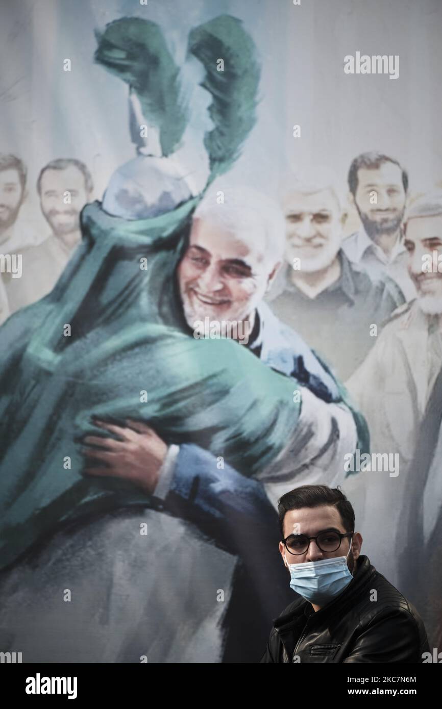 An Iranian man wearing a protective face mask looks on while standing ...