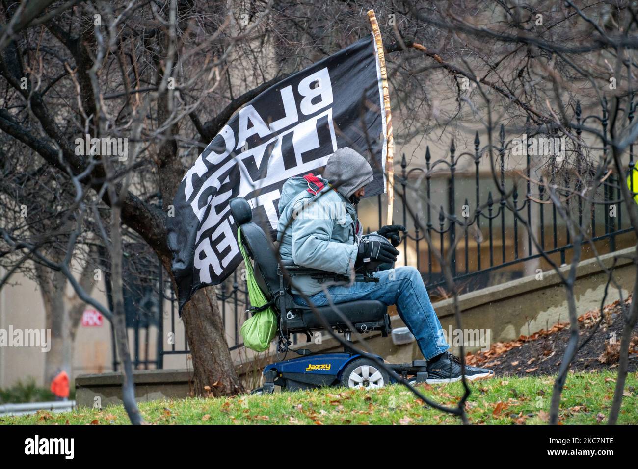 A man in a wheelchair carrying a Black Lives Matter flag is seen during ...