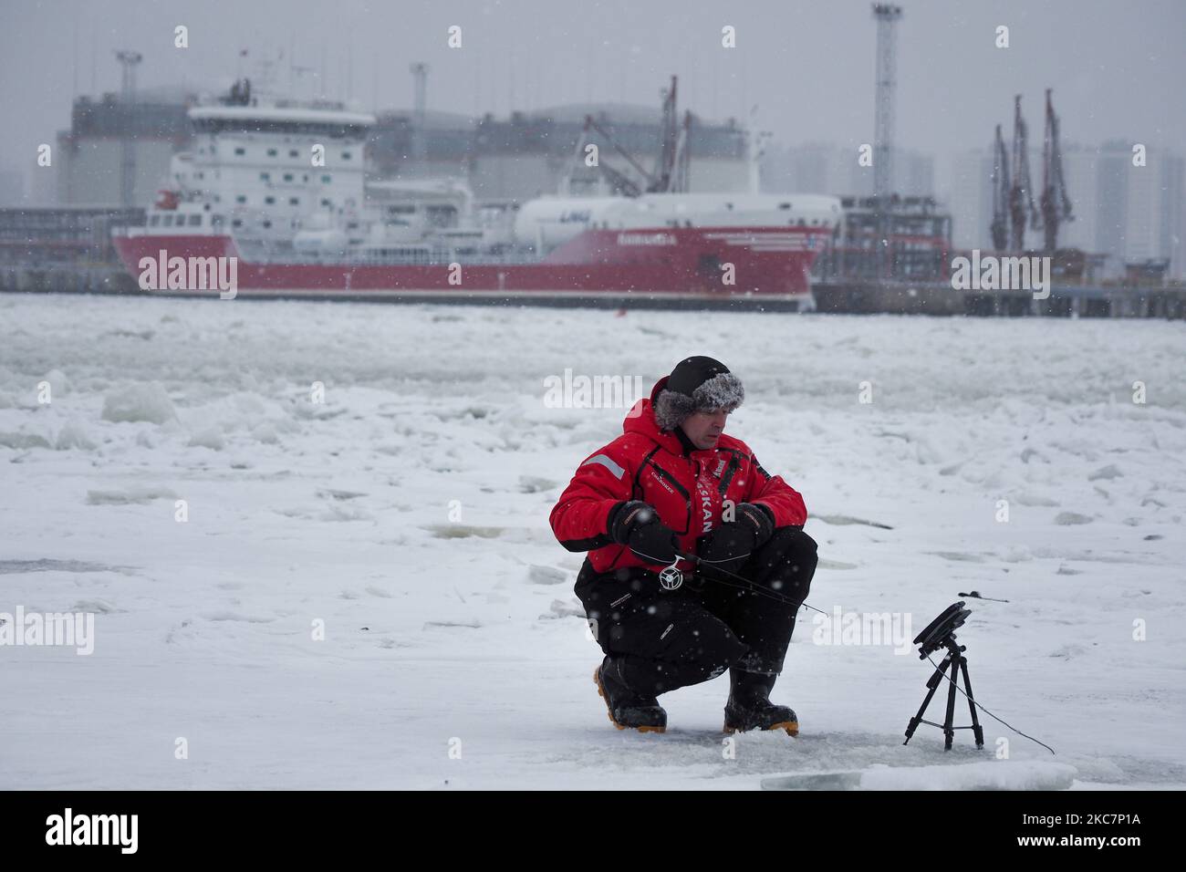 A Russian fisherman fishing on the ice of the Gulf of Finland in St ...