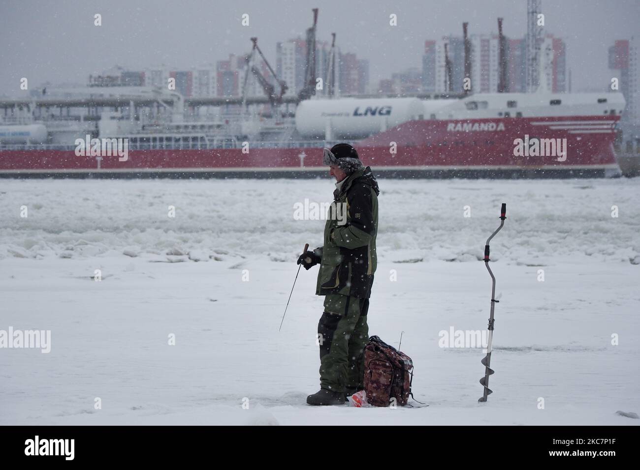 A Russian fisherman fishing on the ice of the Gulf of Finland in St ...