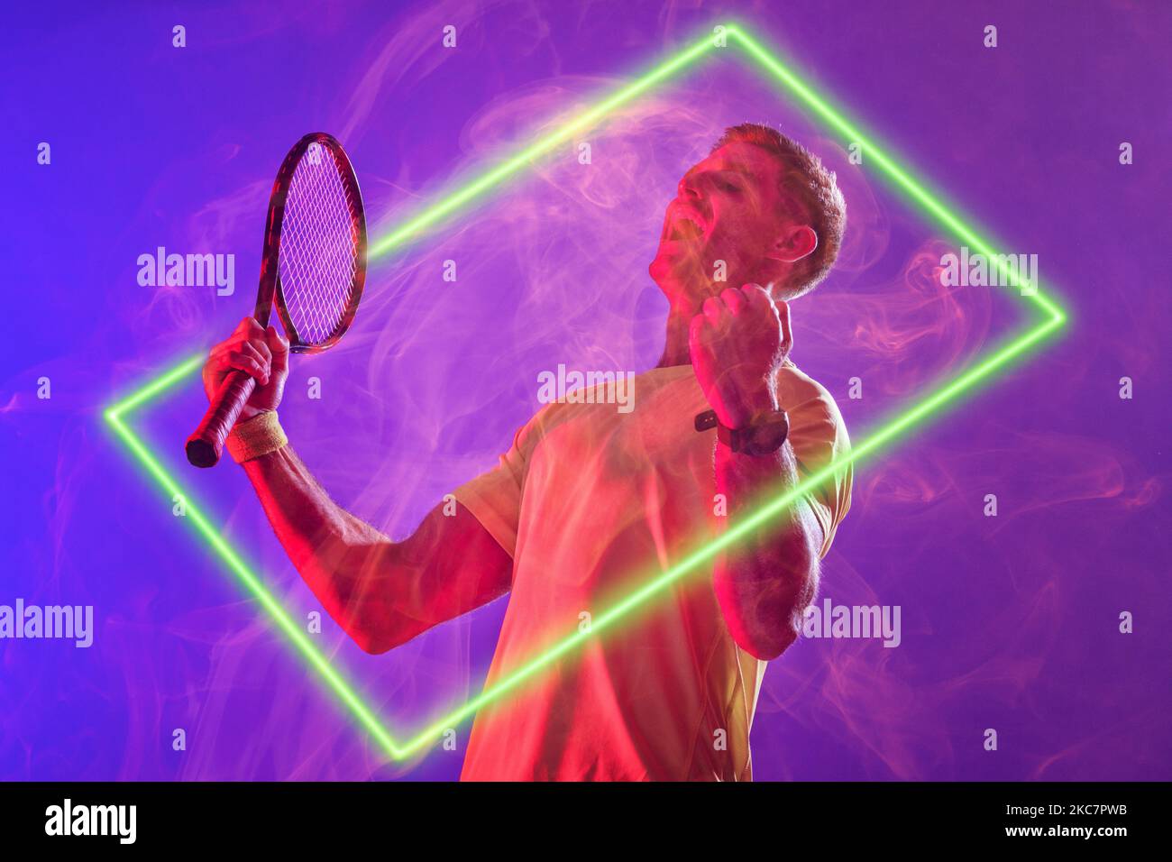 Caucasian tennis player screaming and holding racket by illuminated ...