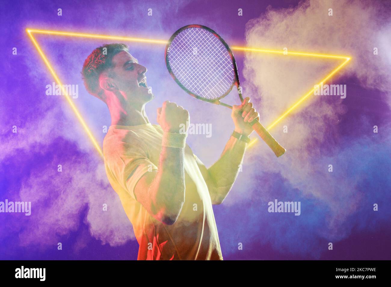 Caucasian male tennis player holding racket screaming by illuminated ...